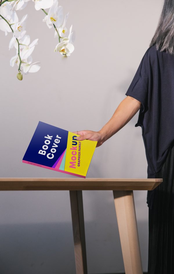 Book cover in hand mockup – GraphicsFamily